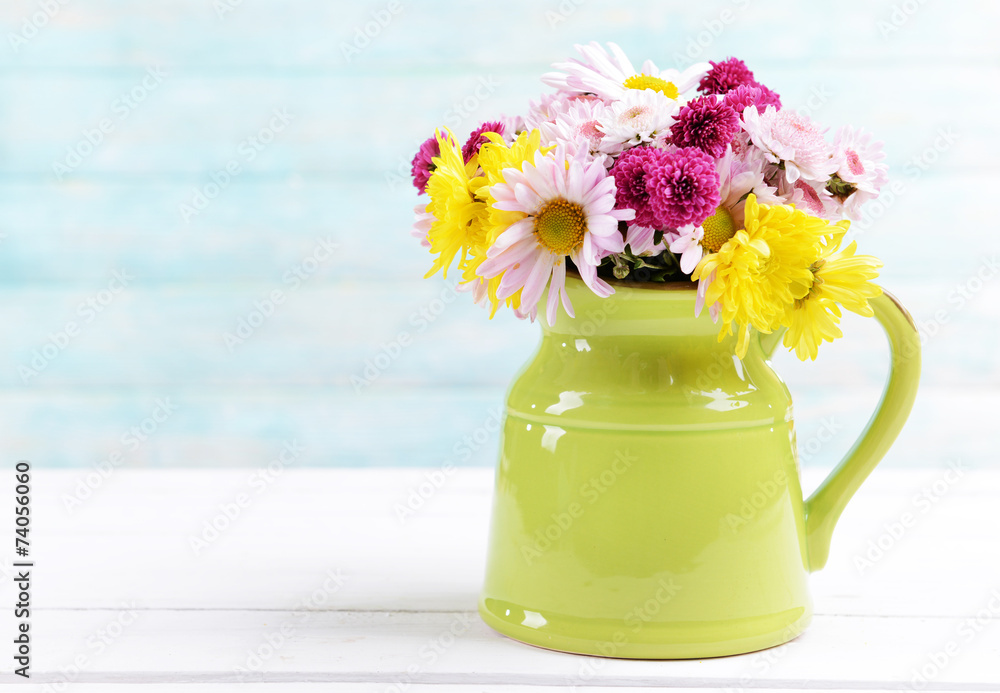 Beautiful flowers in pitcher on table on light blue background Stock ...