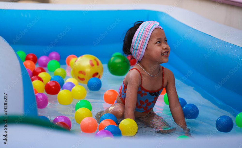 Little girl playing ball in the kiddie pool. Stock Photo | Adobe Stock