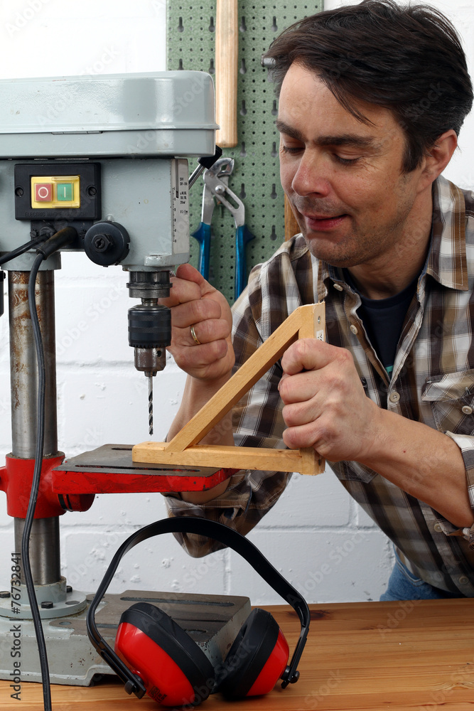 lächelnder Handwerker bohrt mit Standbohrmasch. Stock-Foto | Adobe Stock