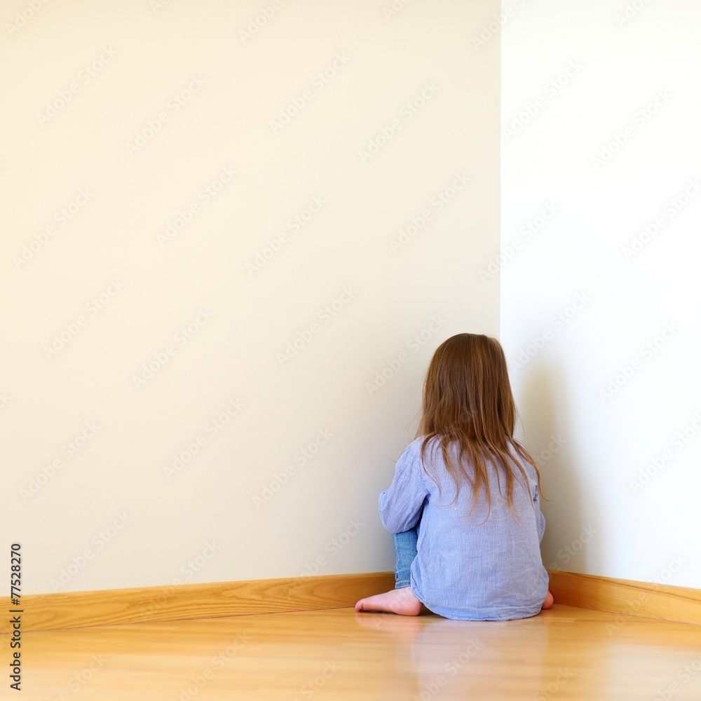 Sad little girl sitting in a corner Stock Photo | Adobe Stock