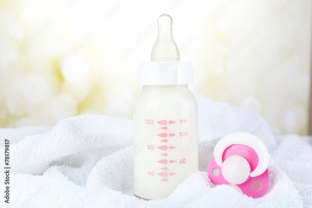 Baby milk bottle and pacifier on towel on bright background Stock Photo ...