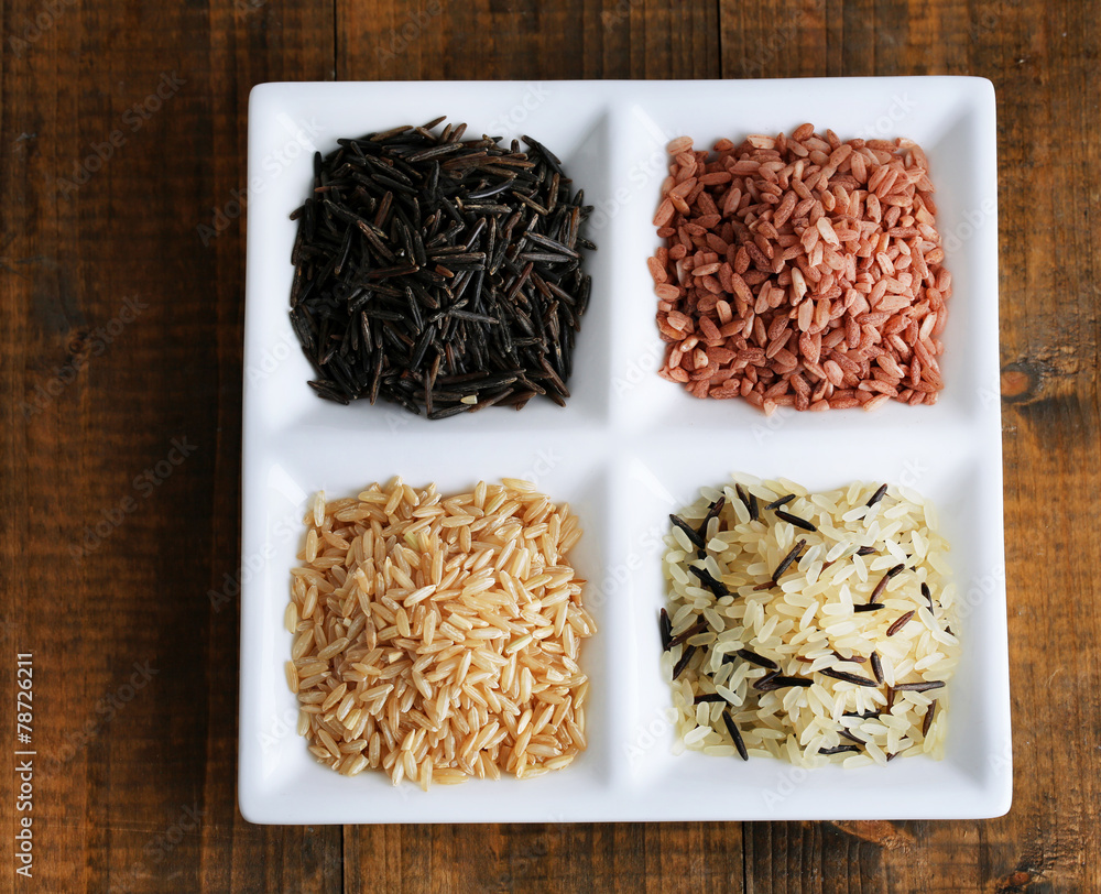 Different types of rice on plate on wooden background Stock Photo ...