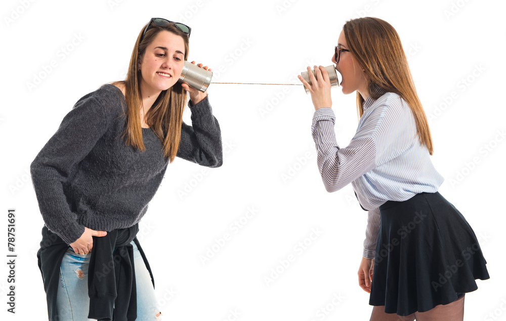 Stockfoto Twin sisters talking through tin phone | Adobe Stock