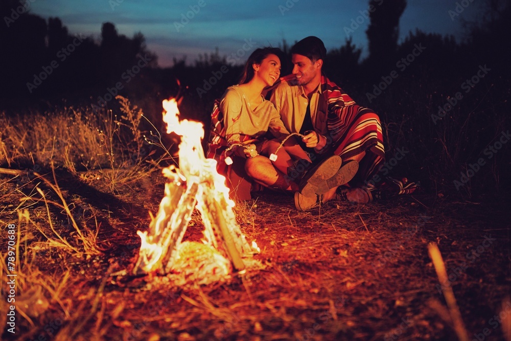 a charming couple sitting around the campfire Stock Photo | Adobe Stock