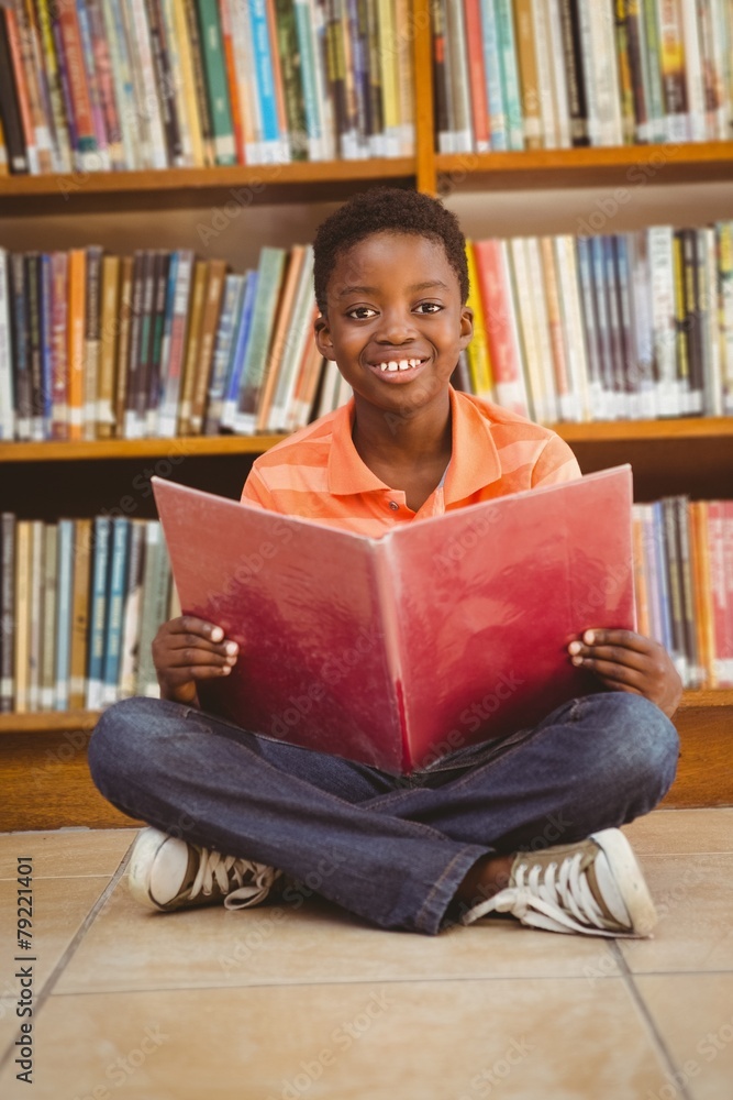 Cute boy reading book in library Stock Photo | Adobe Stock