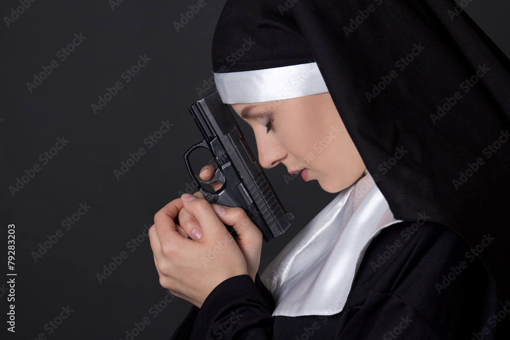 young woman nun praying with gun over grey Stock Photo | Adobe Stock