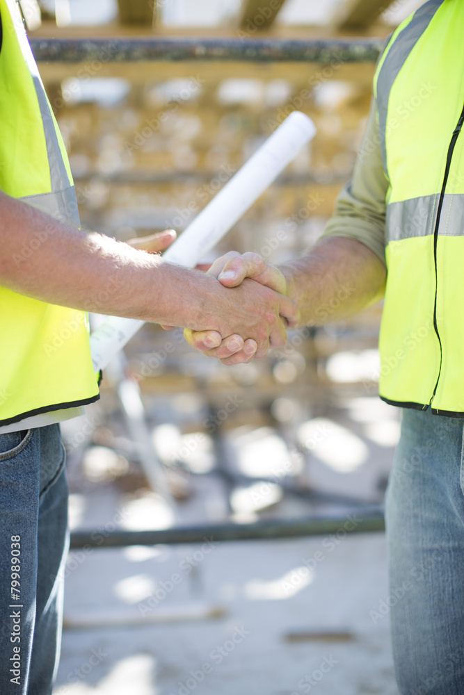 Two construction workers shaking hands in construction site Stock Photo ...