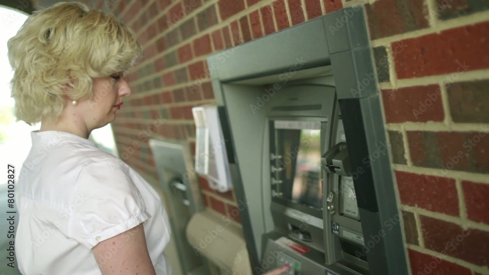 Woman using an ATM, turns to the camera and smiles at end of clip ...