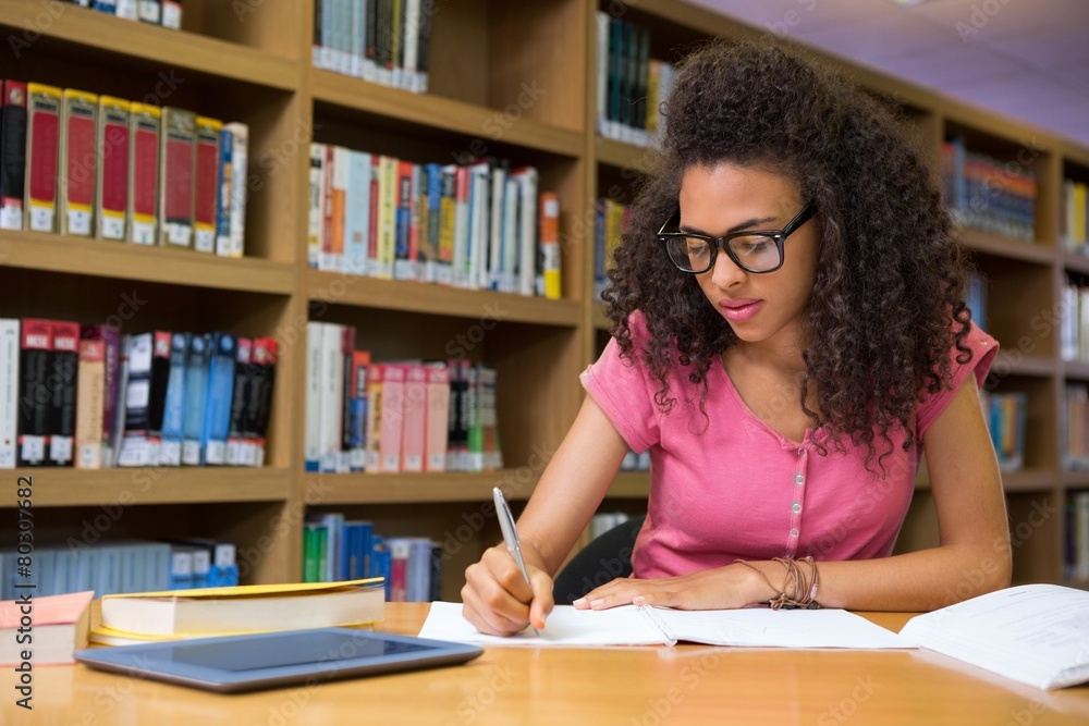 Student sitting in library writing Stock Photo | Adobe Stock