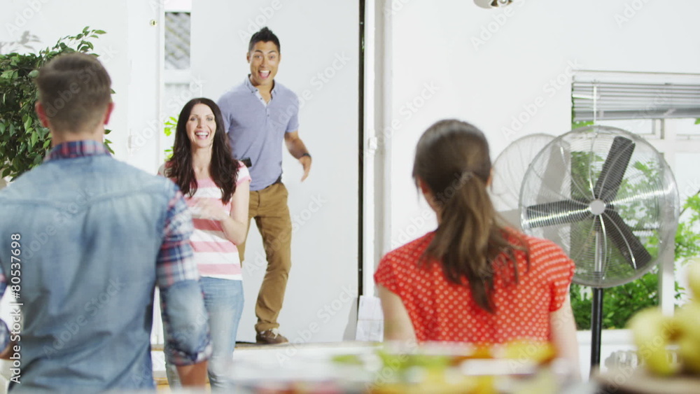 Friendly couple hosting a party at home greet their guests as they ...