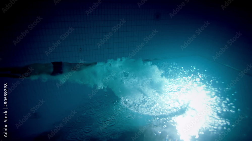 Underwater view of a professional male swimmer diving into deep blue ...