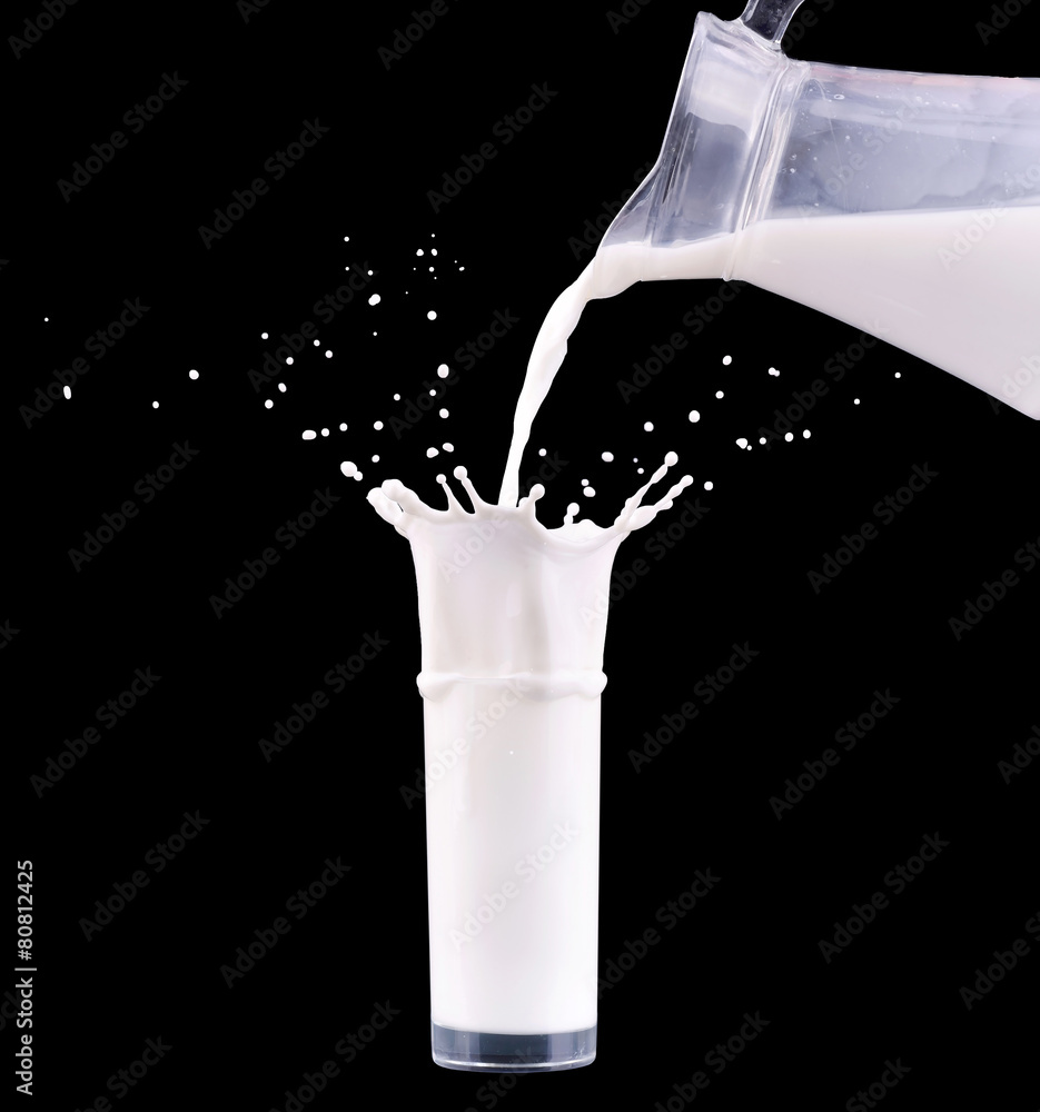 Milk pouring from jug bottle into glass with splash on black Stock ...