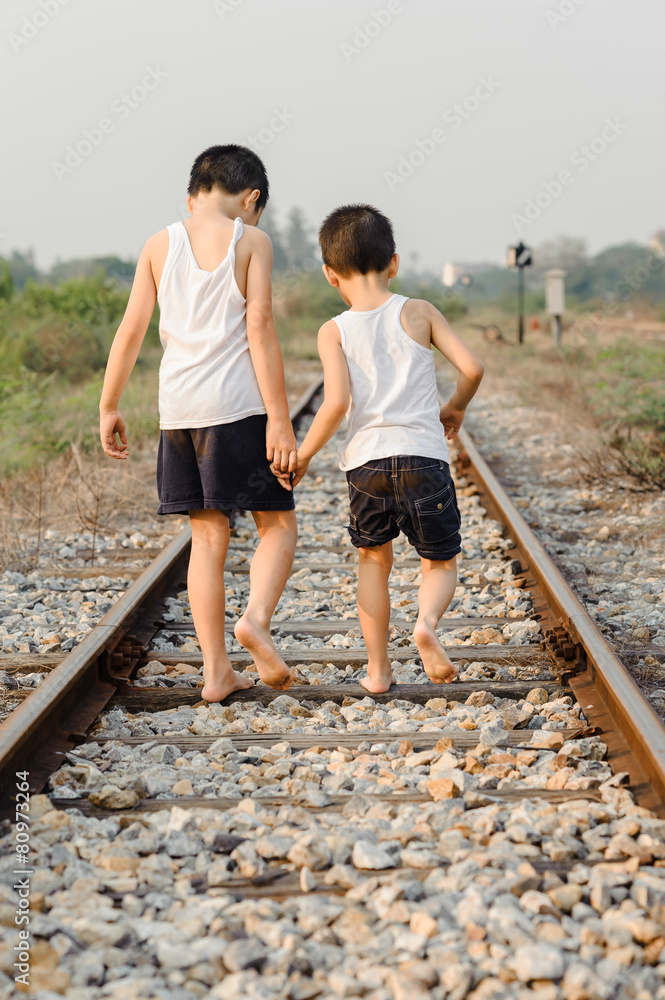 two boys walk on the railway Photos | Adobe Stock