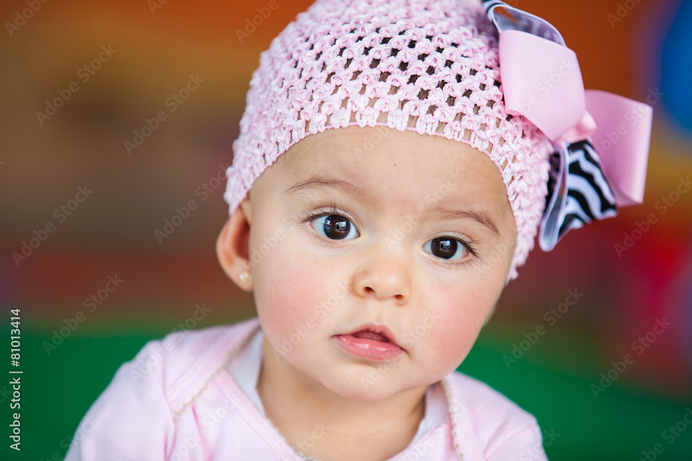 Rostro de una hermosa bebita de seis meses vestida de rosa en actitud pensativa con un fondo ...