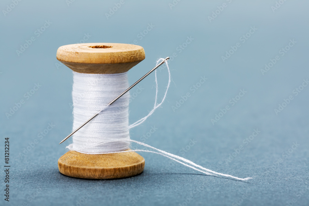 Spool of white sewing thread and needle Stock Photo | Adobe Stock