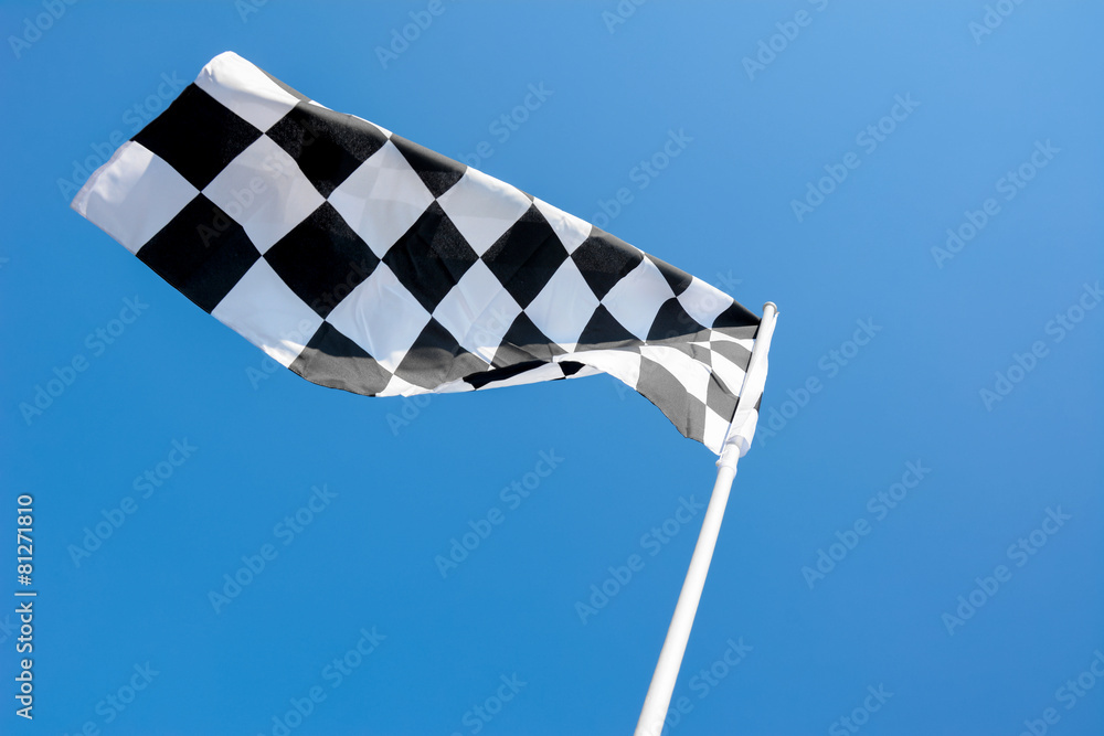 Checkered flag flying on blue sky background Stock Photo | Adobe Stock
