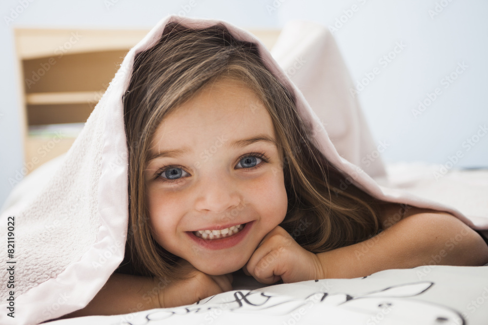 Caucasian girl smiling under covers Stock Photo | Adobe Stock