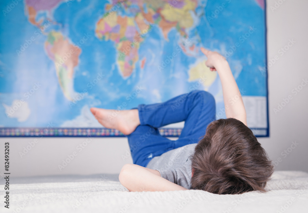 Boy lying on sofa and studying map of world Stock Photo | Adobe Stock