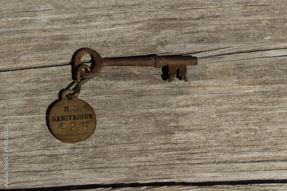 Old rusty skeleton key to a sanitarium / mental hospital on a wood ...