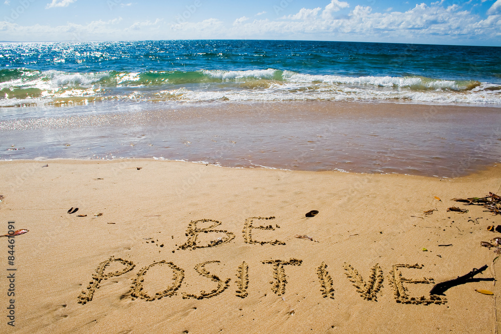 Be positive. Creative motivation concept written in the sand at the ...