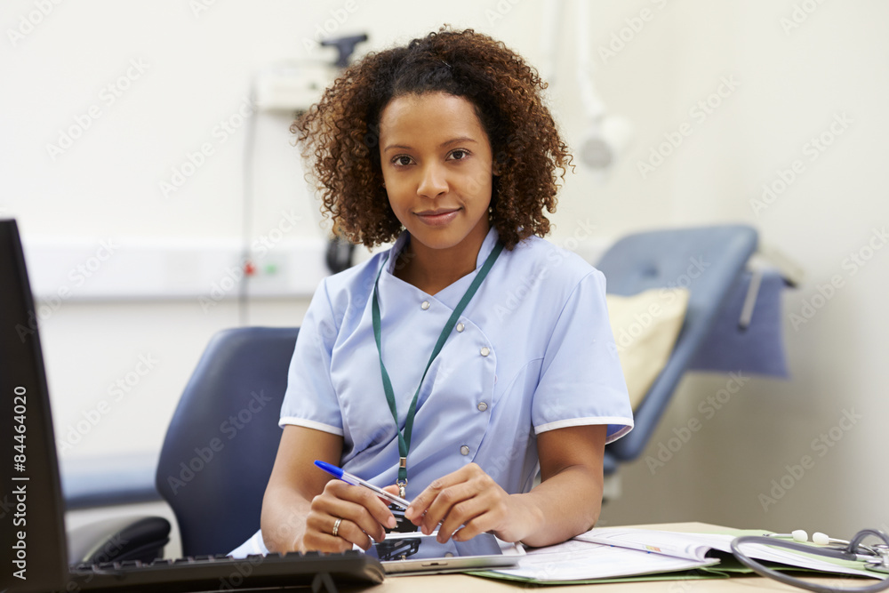Portrait Of Female Nurse Working At Desk In Office Stock Photo | Adobe ...