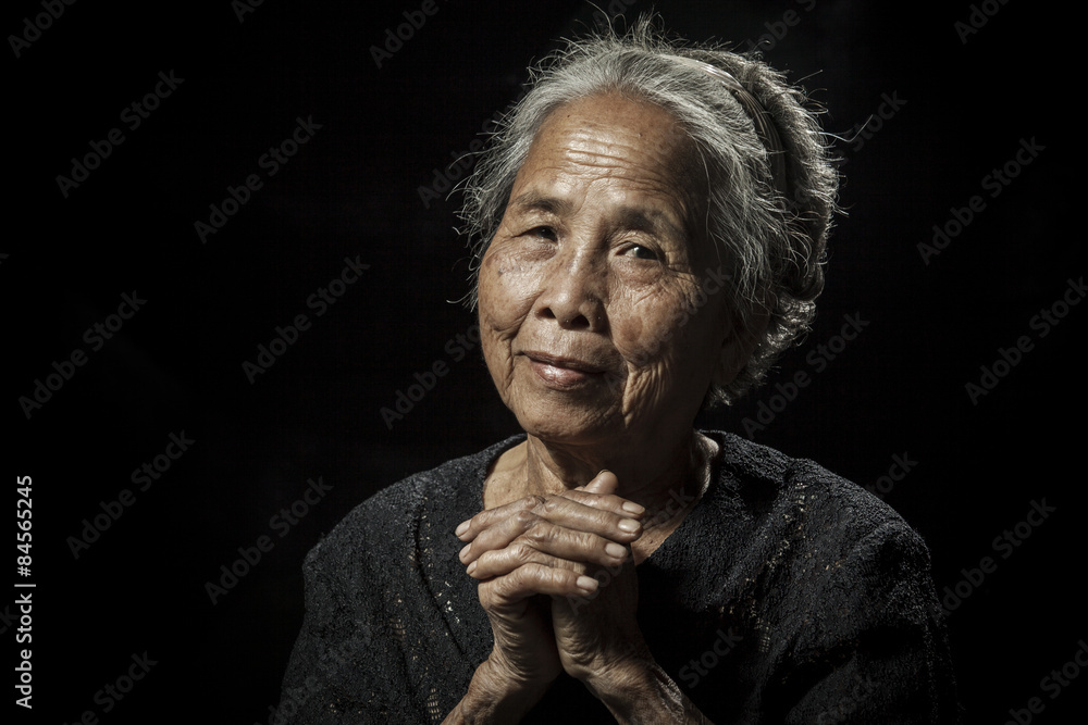 Old woman praying on black background Stock Photo | Adobe Stock