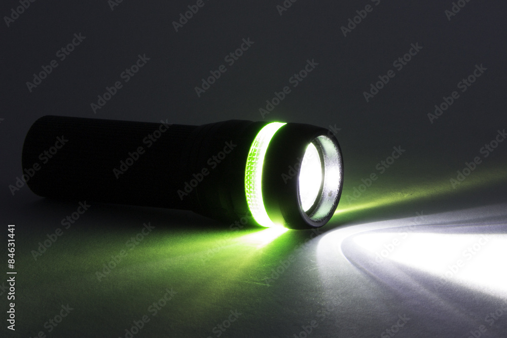 black flashlight lighting up shines green and white ray light beam ...