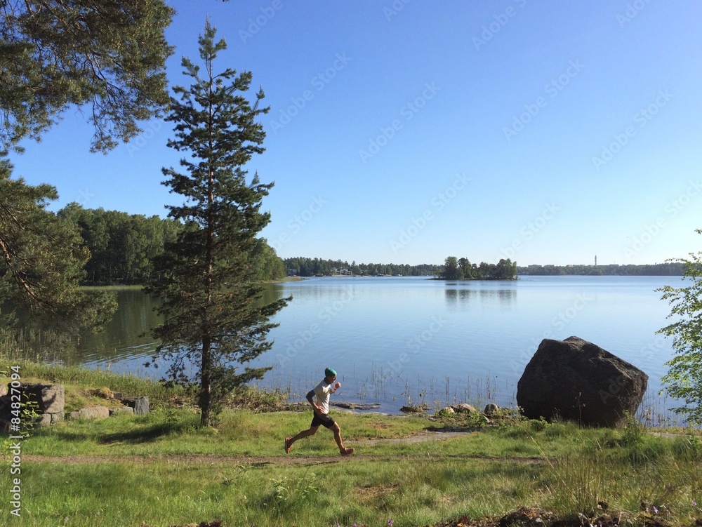 runner on trail next to blue lake on beautiful day Stock Photo | Adobe ...