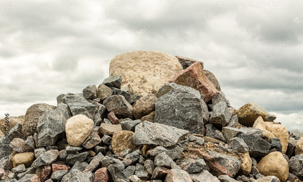 big pile of rocks and boulders piled in a heap under a grey dark cloudy ...