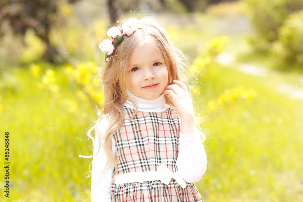 Smiling cute baby girl posing over green nature background. Wearing ...