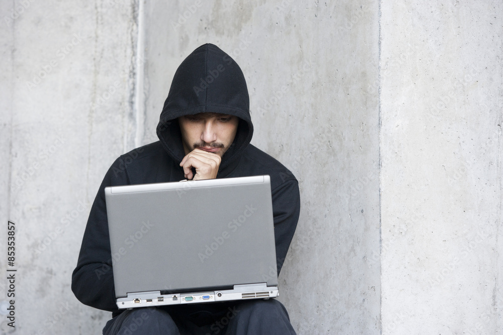 Hacker with laptop sitting in an underground car park Stock Photo ...