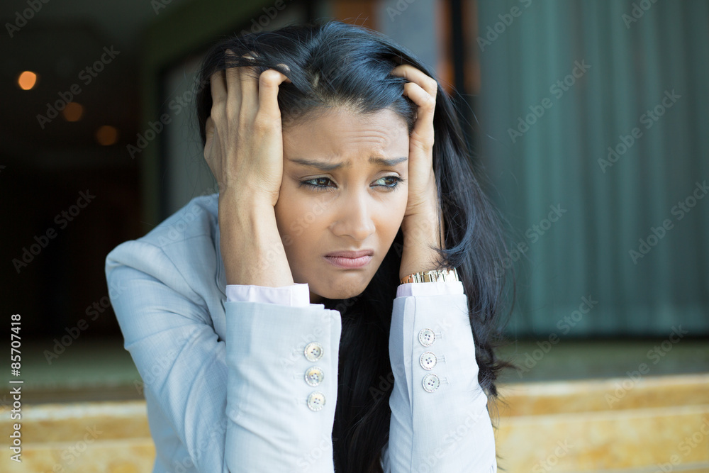 Closeup portrait, sad young woman in white gray suit sitting on stairs ...