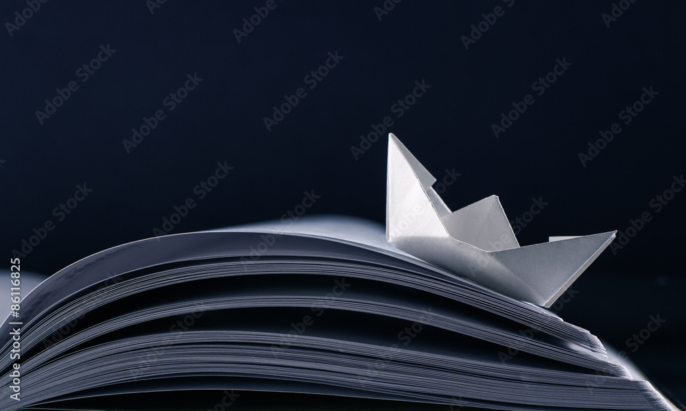 Paper boat floating on the pages of a notebook. Stock-Foto | Adobe Stock