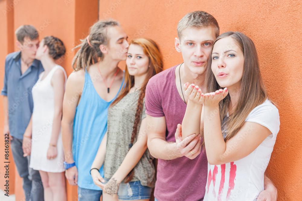 Group of happy young people standing in pairs near the wall and they ...
