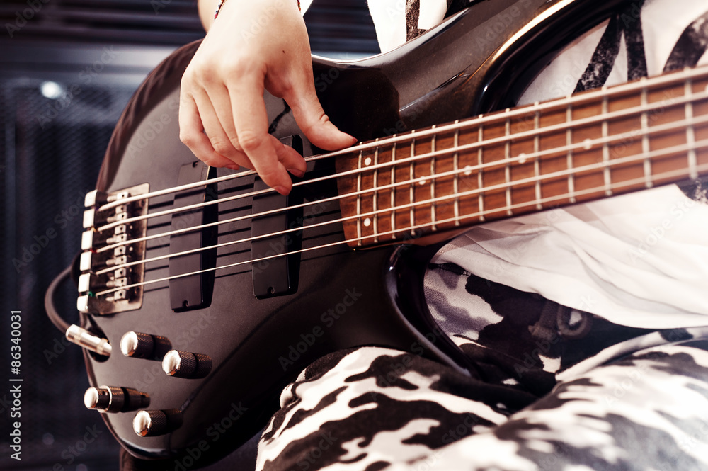 Young adult girl playing five string bass guitar. Color image in ...