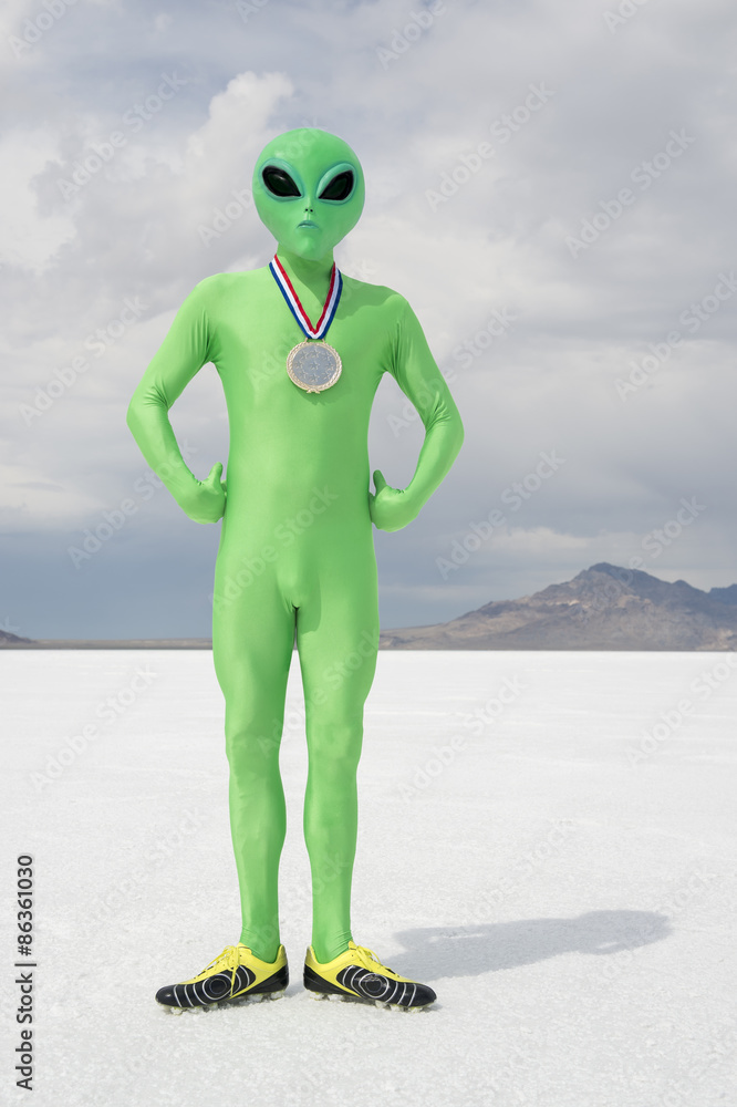 Green alien athlete wearing gold medal standing on stark white planet ...