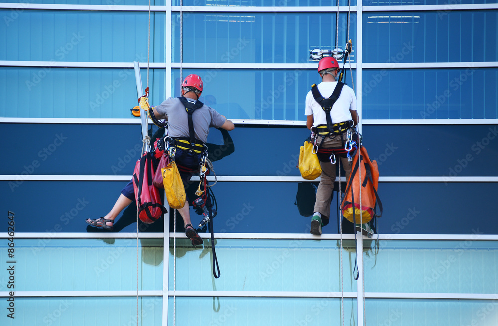 Two construction workers working at height on modern commercial ...