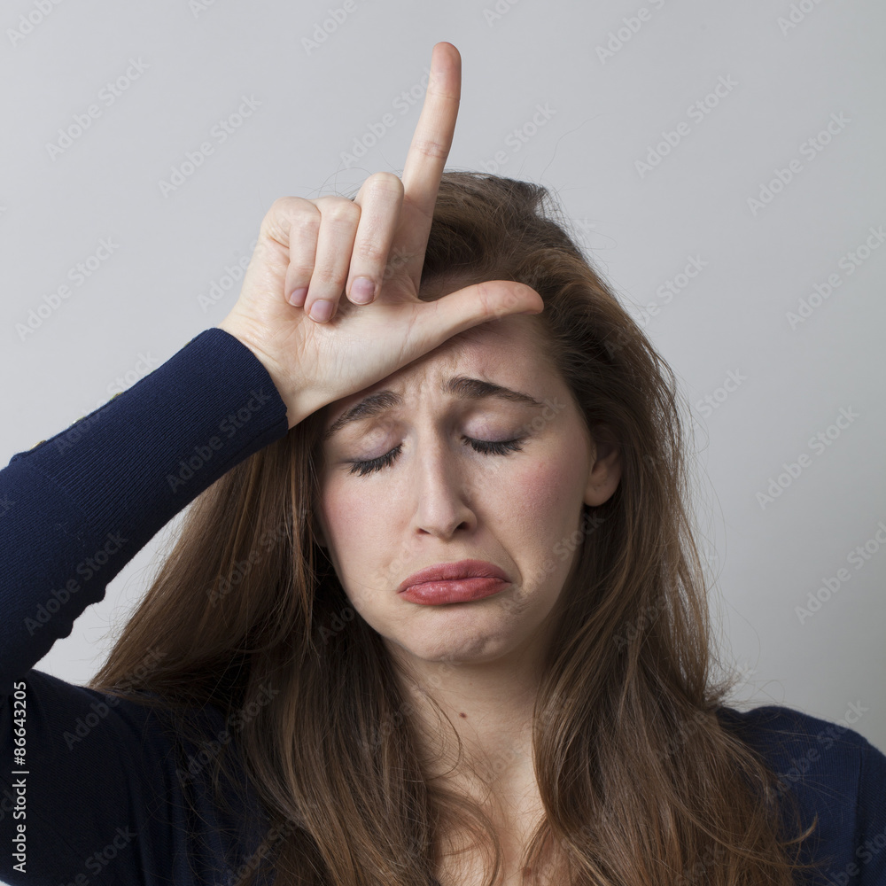 crying young woman making the L sign on forehead for loser message ...