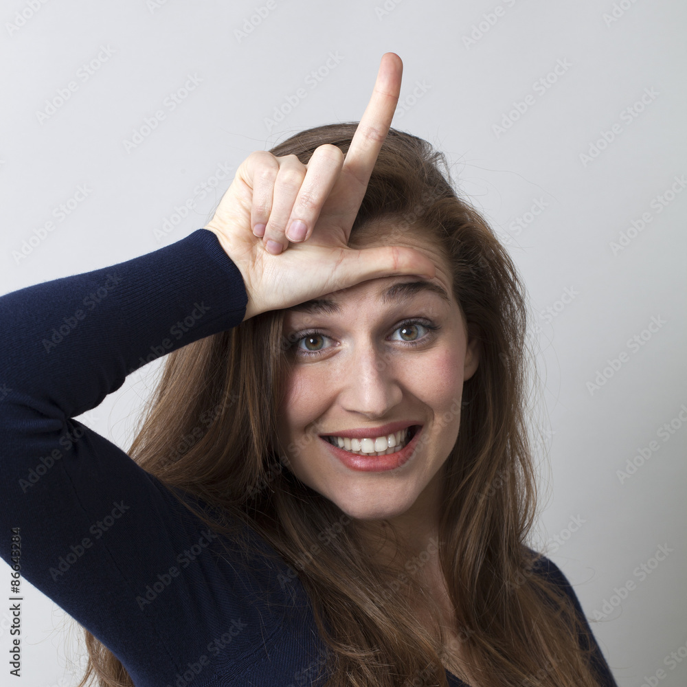 surprised young woman making the L sign on forehead for loser message ...
