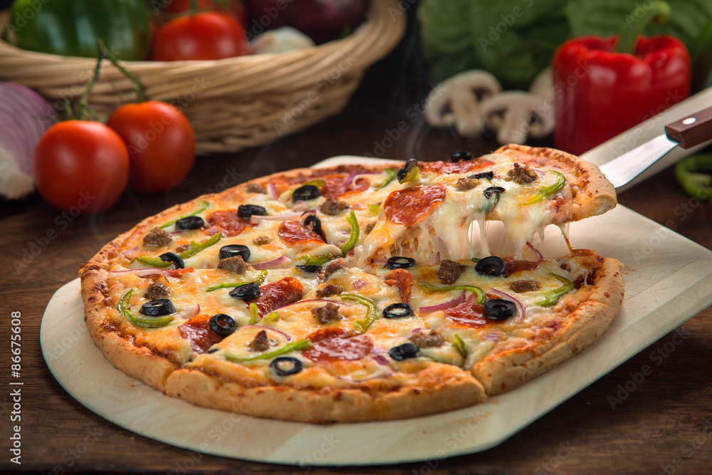 Hot cheese deluxe supreme pizza on a table restaurant style cutting ...