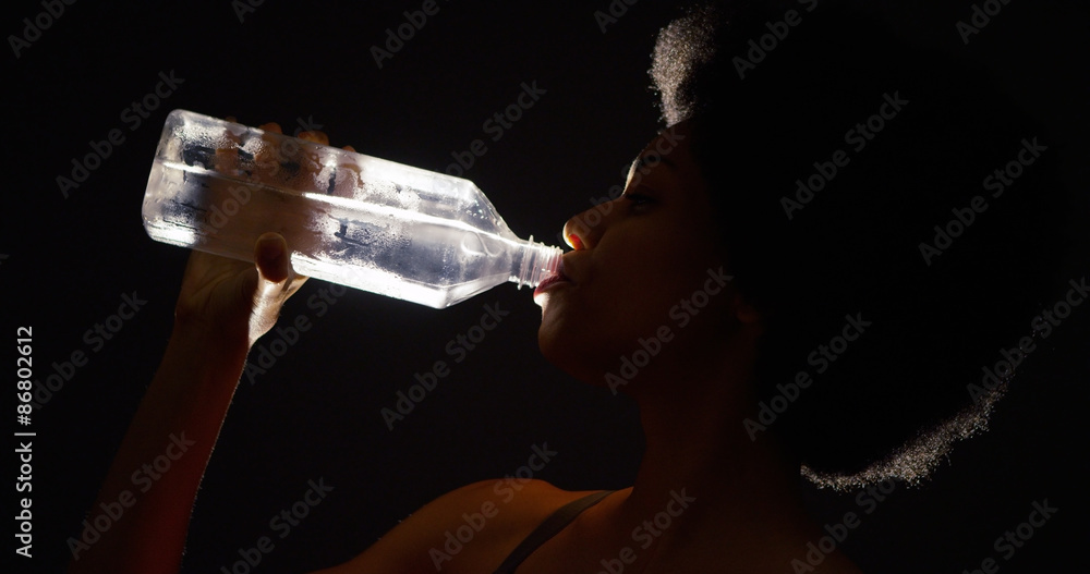 Backlit studio shot of black woman drinking water from bottle Stock ...