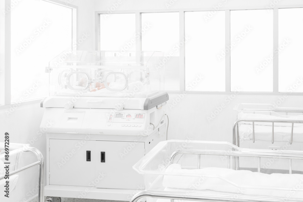 Newborn baby covered inside incubator in hospital post-delivery room ...