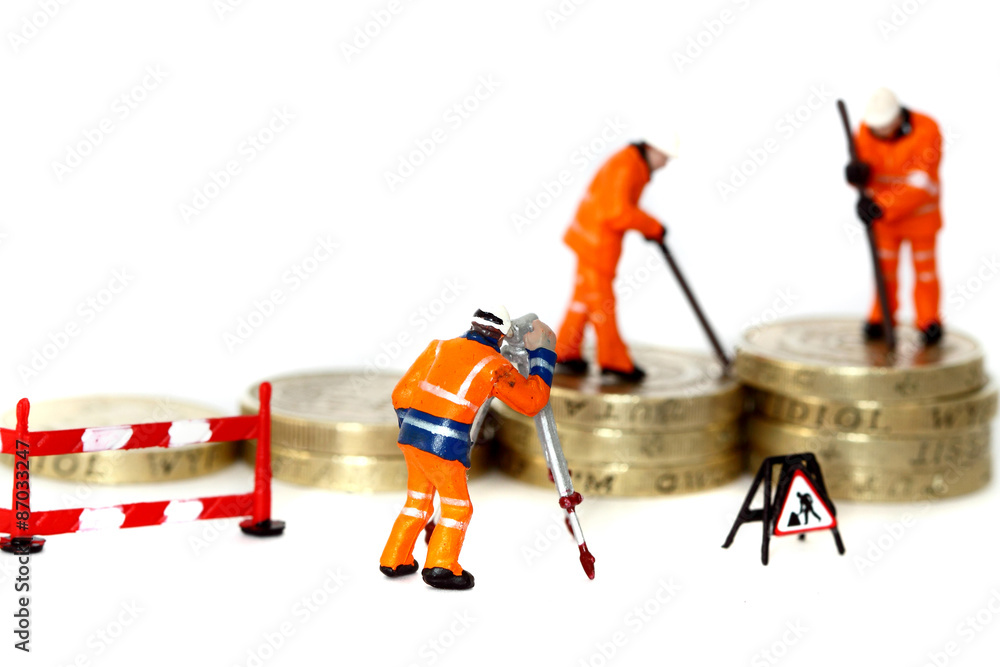 Miniature construction workers pound coins. Miniature scale model ...