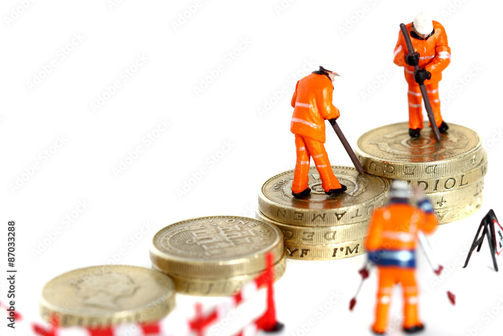 Miniature construction workers pound coins. Miniature scale model ...