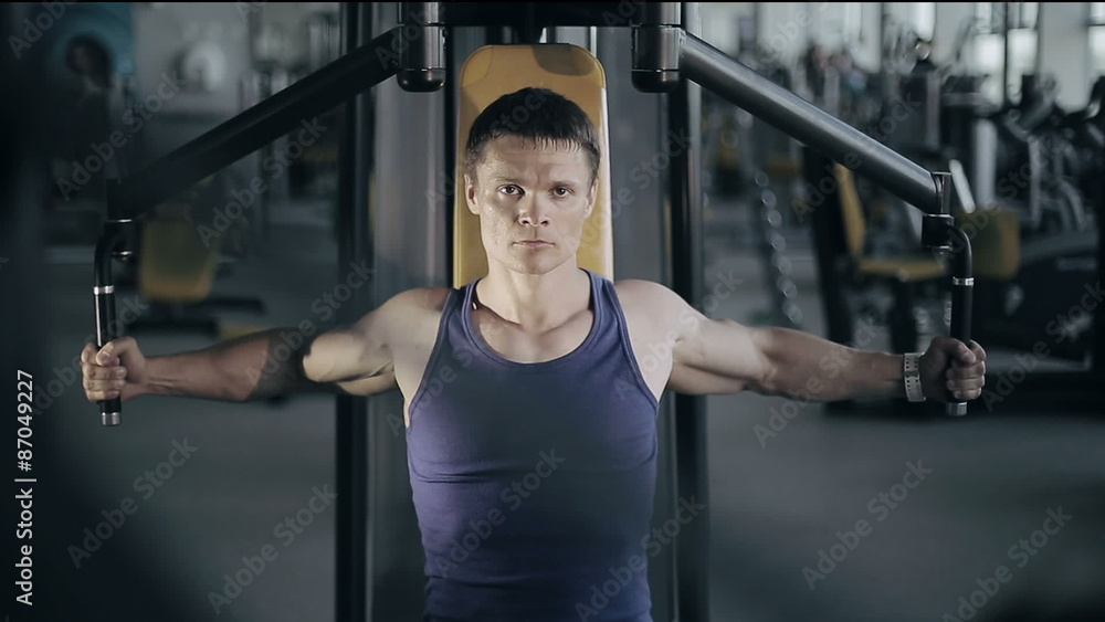 Muscular bodybuilder doing exercises workout in gym for breast muscles ...