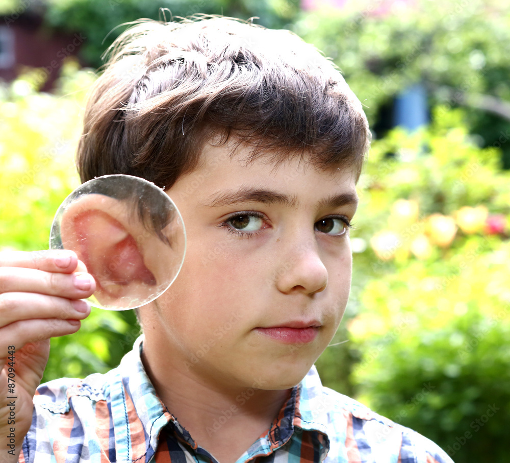 teen boy magnify his ear with lense on the summer background Stock-Foto ...