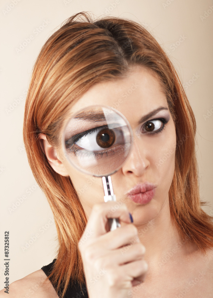 Young woman looking through a magnifying glass Stock Photo | Adobe Stock