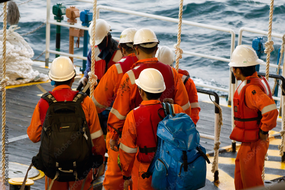 Rig workers using a swing rope prior of being transported to nearby ...