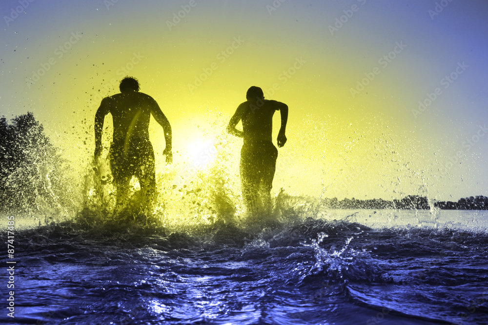 Glückliche junge Menschen laufen und springen am See beim ...