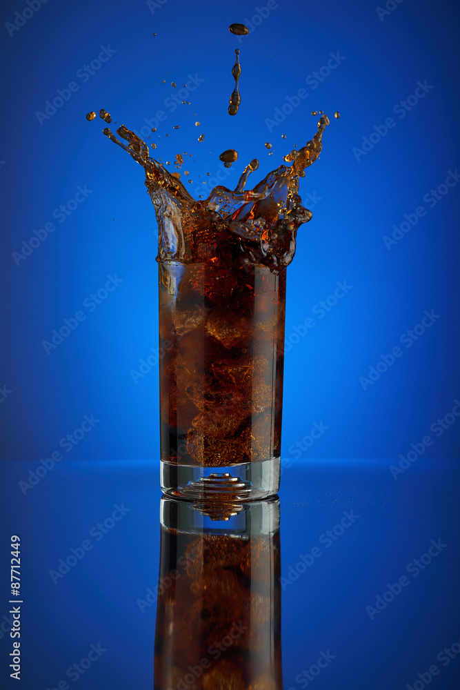 Splash of cola soft drink on a blue background. Refreshing liquid drink ...
